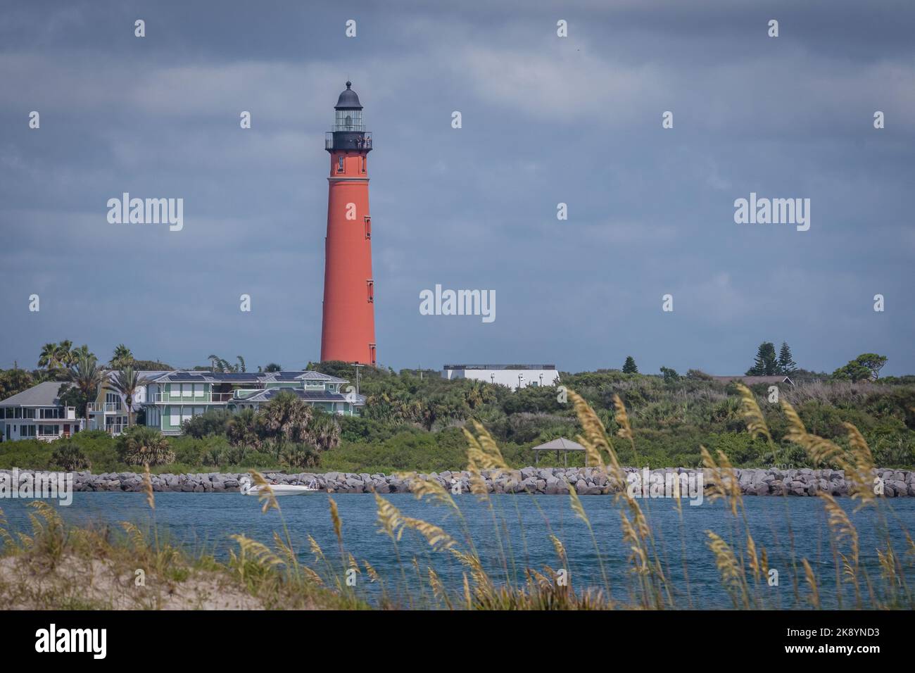 A beautiful scene of a red lighthouse near the body of water on a ...