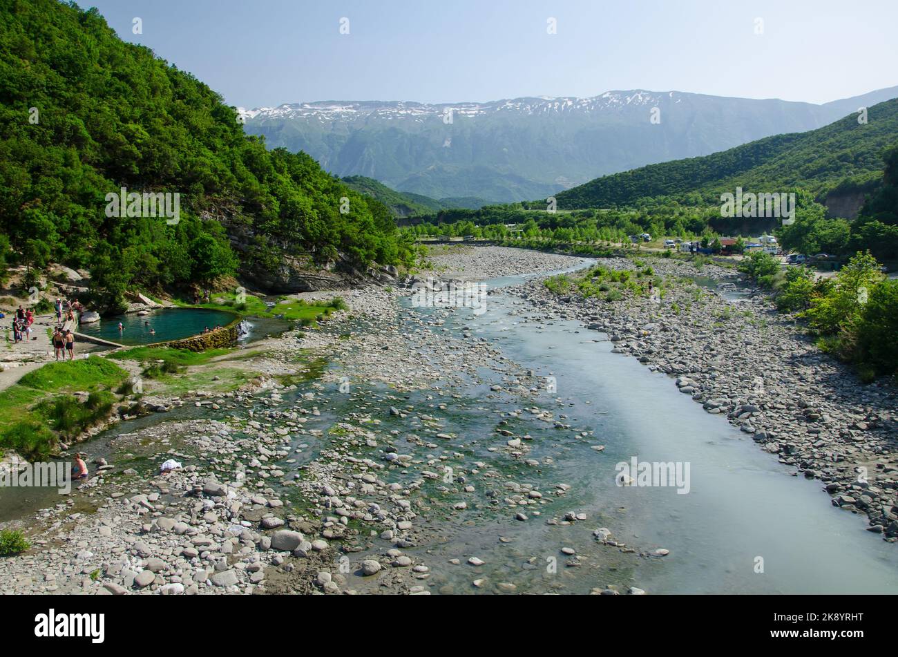 A scenic view of a stream and pond surrounded by mountain forests under ...