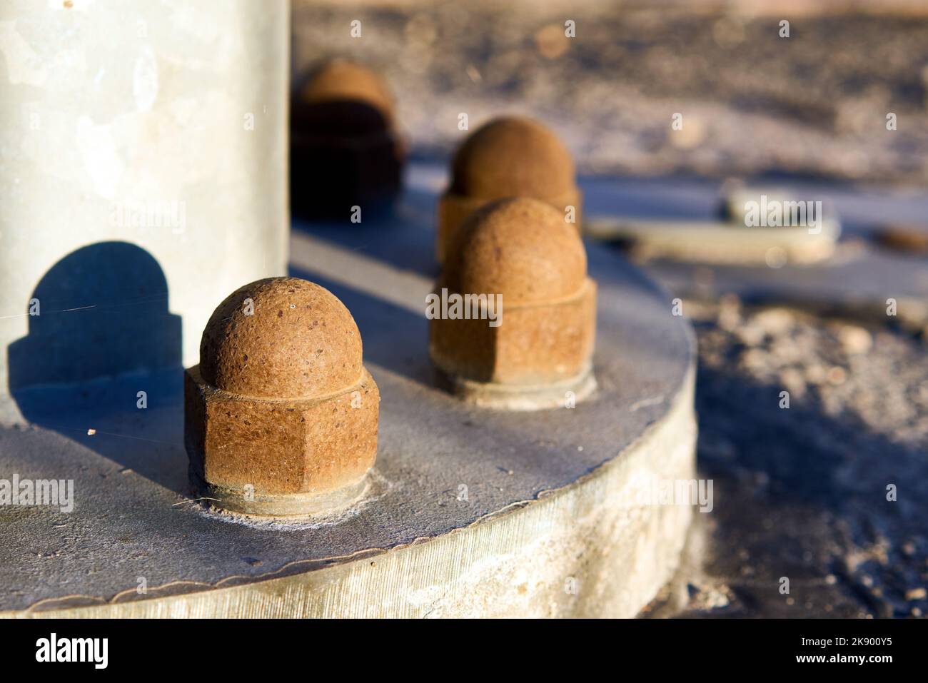 A selective focus shot of rusty metal nuts holding a concrete post on ...