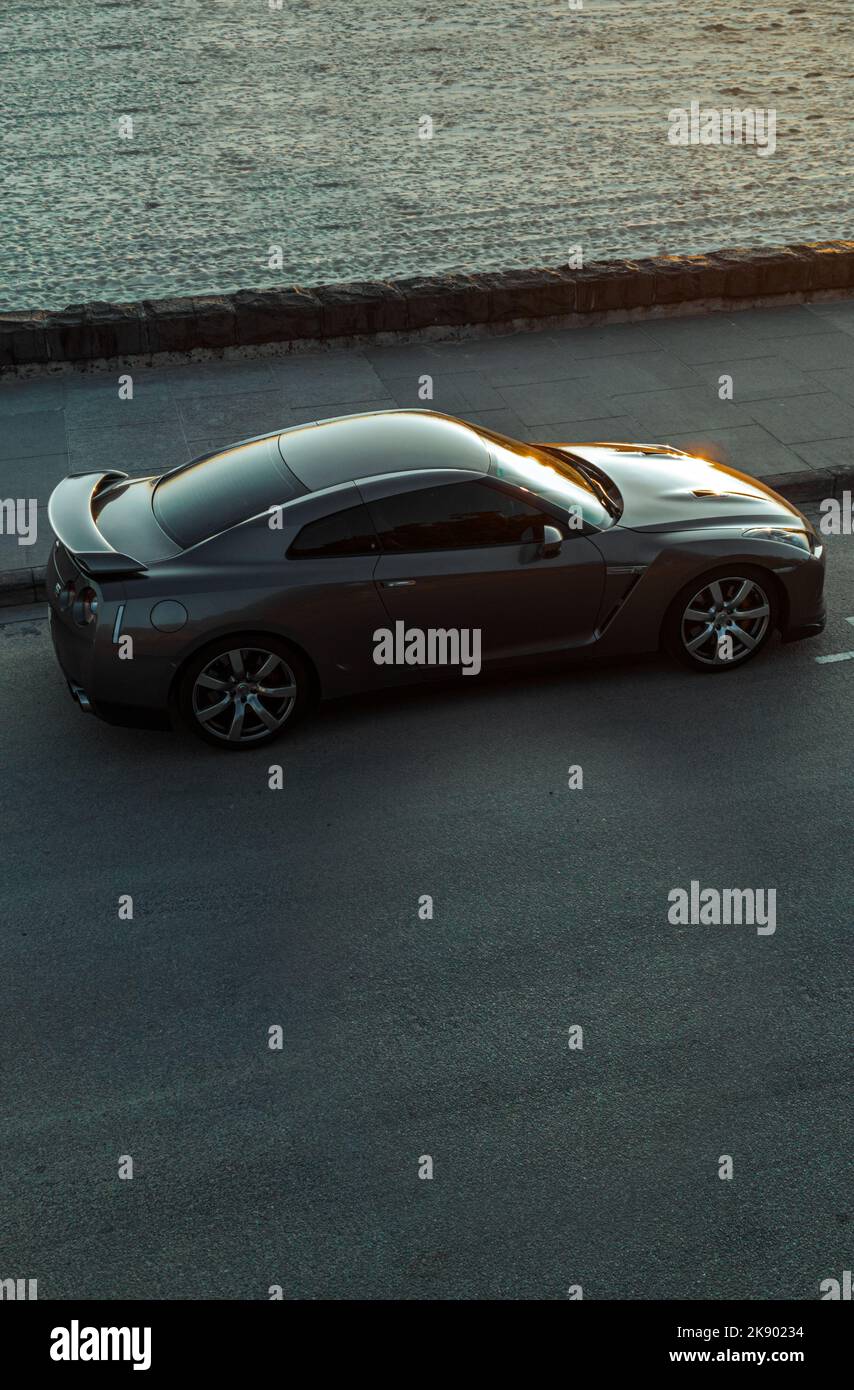 A vertical shot of grey Nissan GT-R car with Beautiful Sunset ...