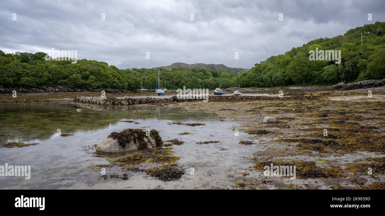 A low-angle shot of very shallow lake water with exposed land and boats ...