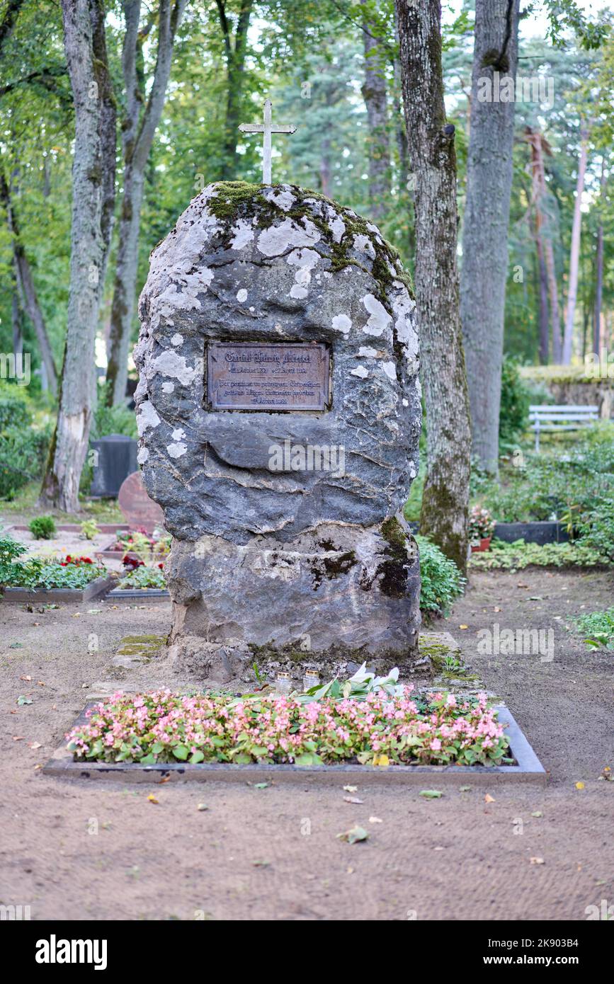 A vertical shot of a gravestone with flowers in front of it in a ...