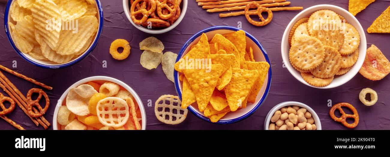 Salty snacks panorama. A table of assorted appetizers in bowls ...
