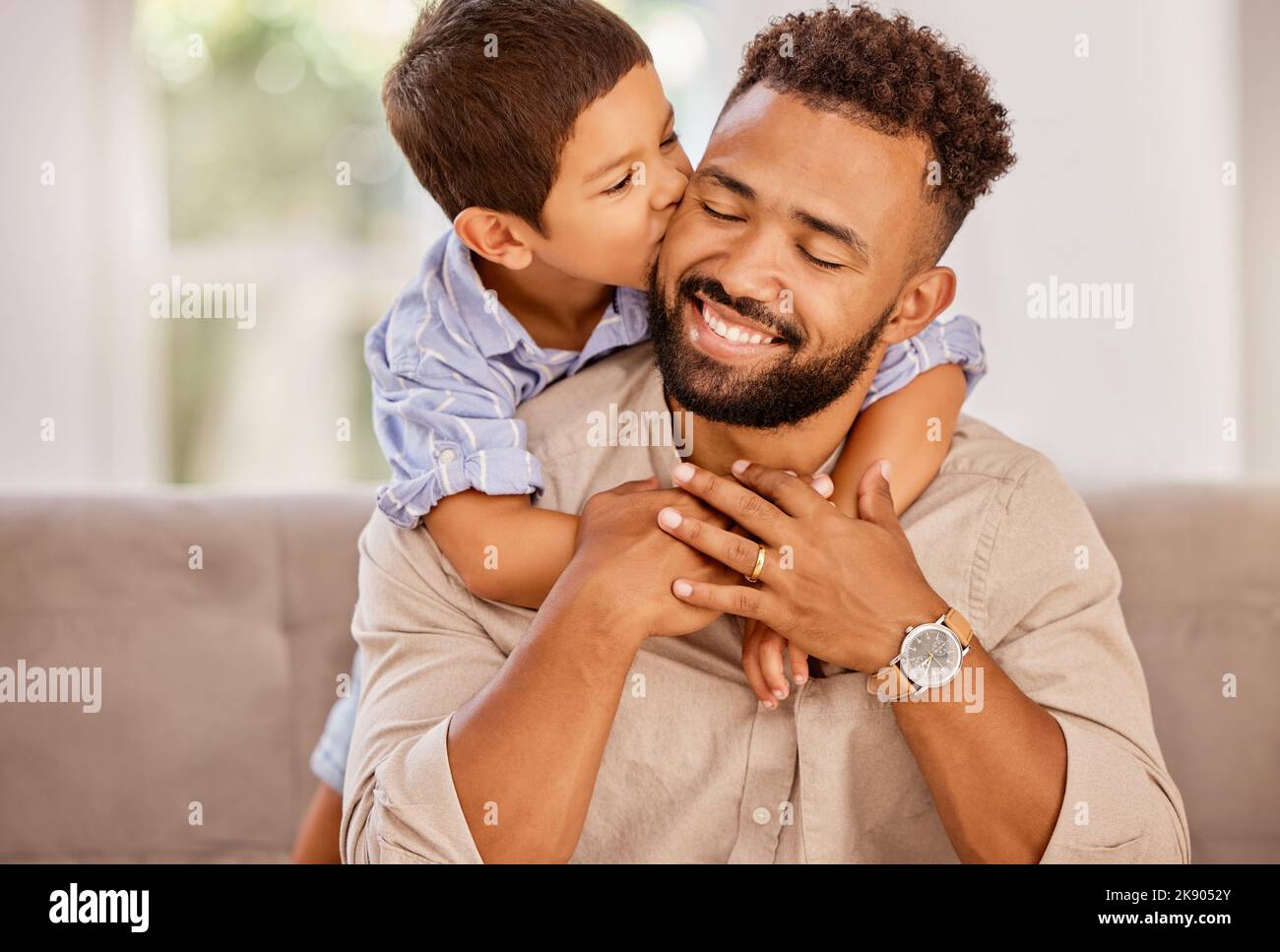 Kiss, father and child with hug on the sofa of their living room in ...