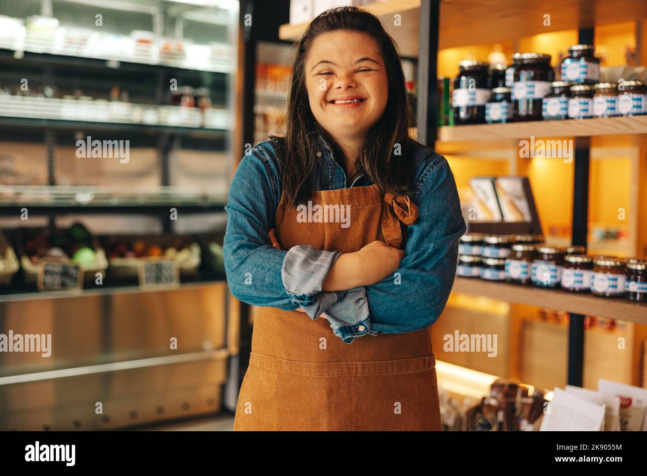 Shop worker with Down syndrome smiling at the camera while standing in ...