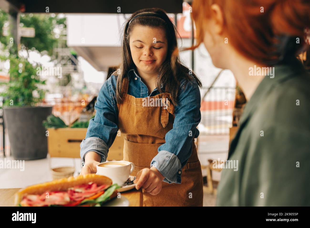 Waitron with Down syndrome serving a customer a sandwich and coffee in ...