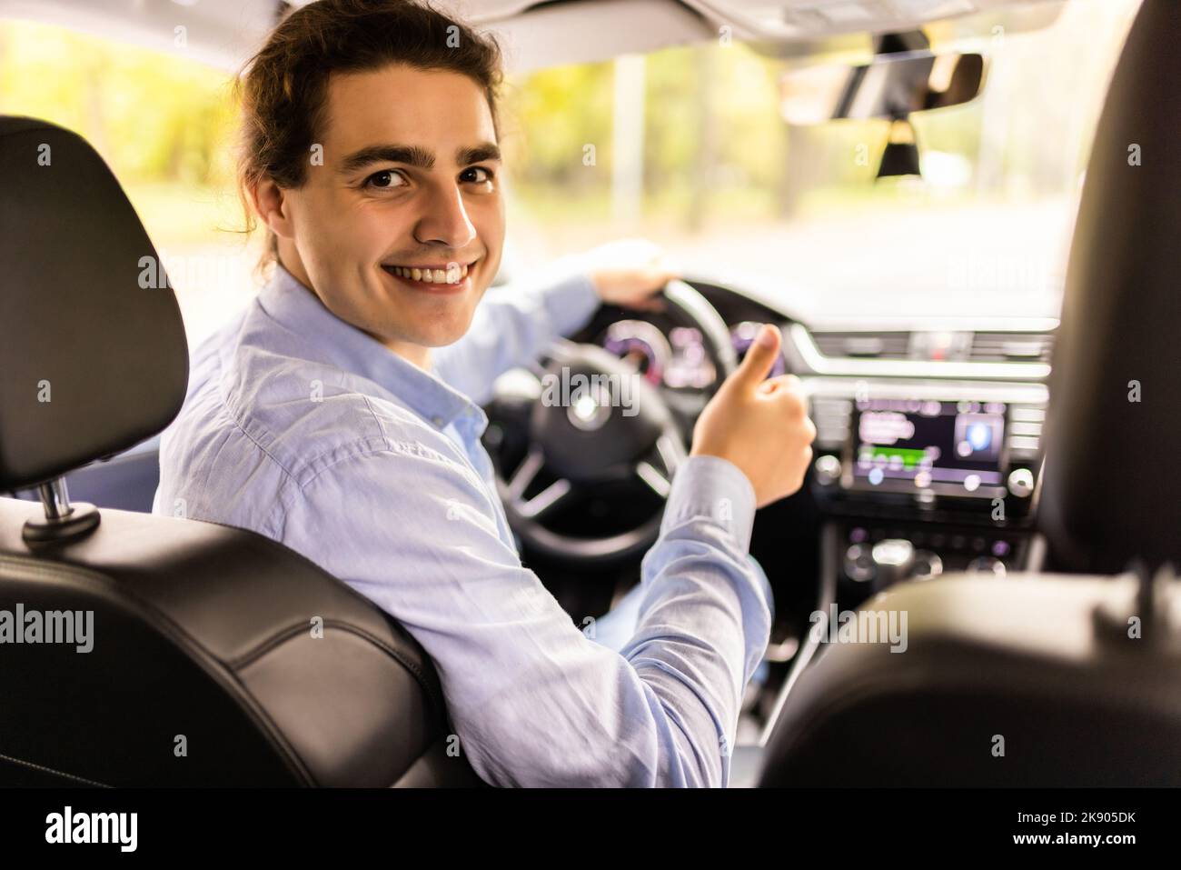 Portrait of a man looking back sitting on the front seat of the car ...