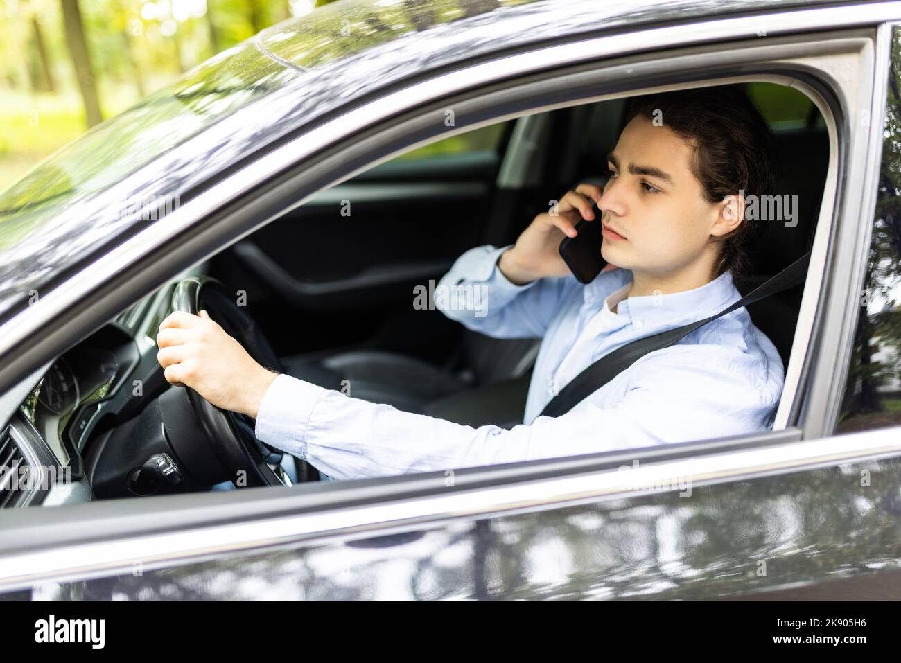 Side view of driver talking on mobile phone and watching for the road ...
