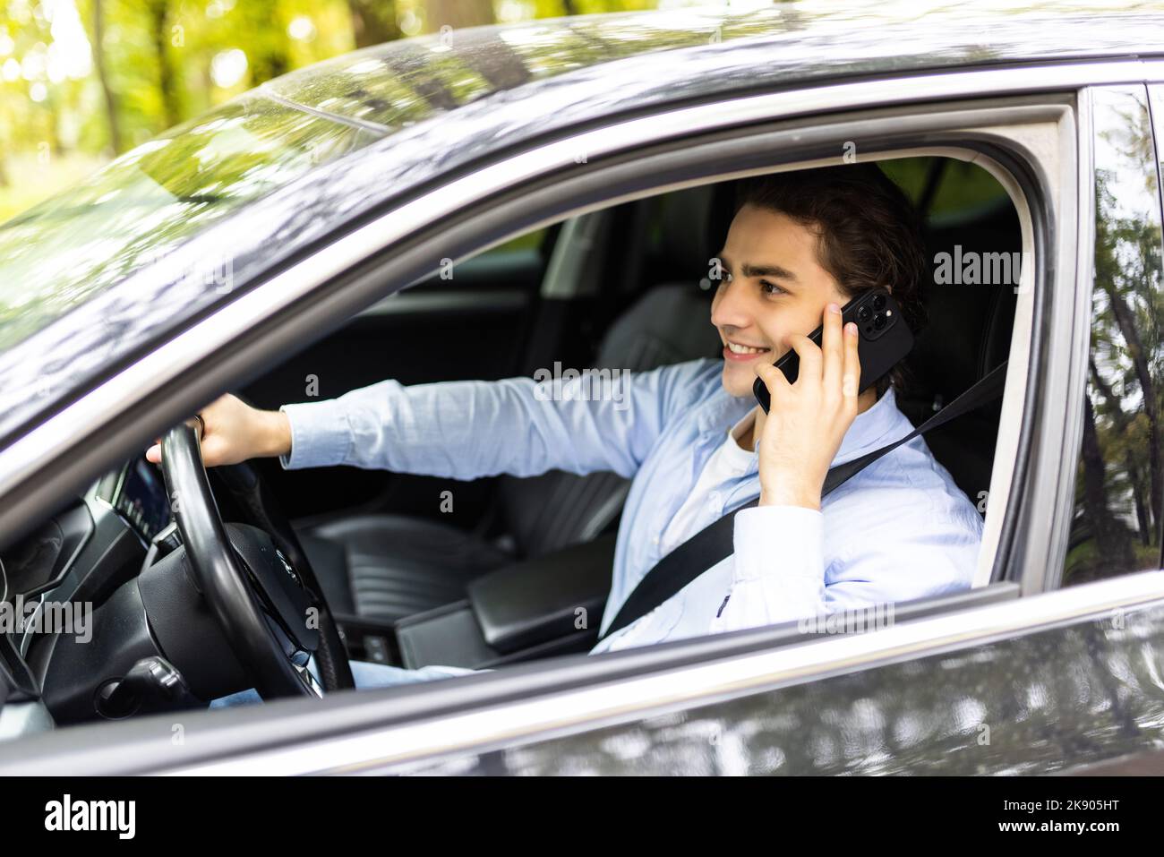 Side view of driver talking on mobile phone and watching for the road ...