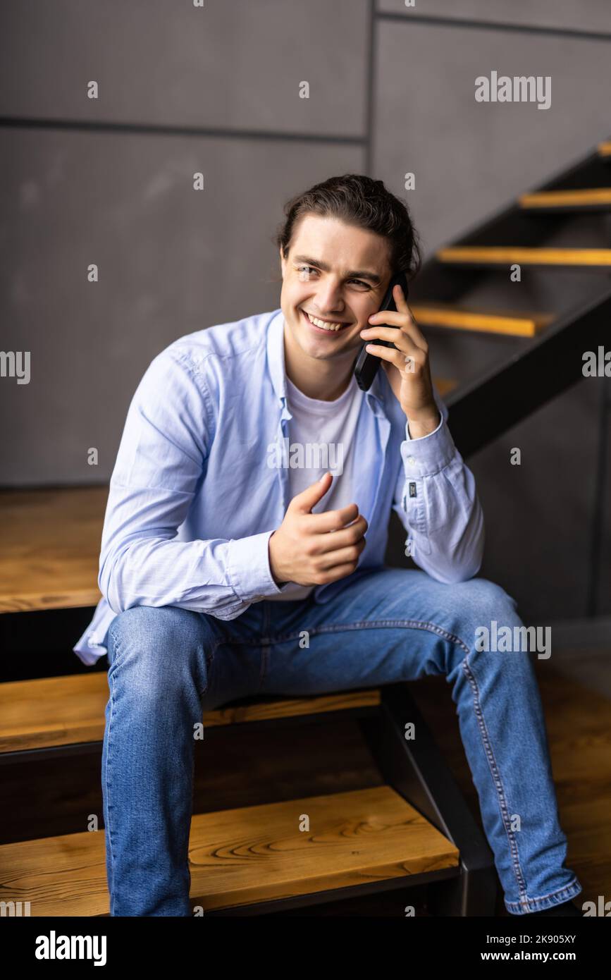Business man sitting indoors on stairs near flower pots with plants and ...