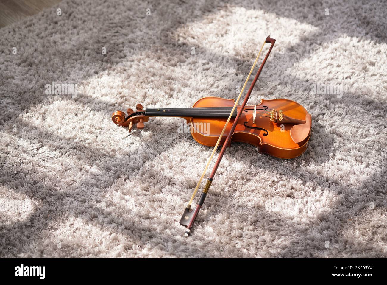 Violin, classic string instrument with bow, on light brown carpet ...