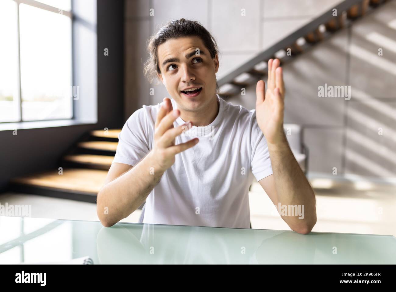 Portrait happy smiling young man waving hand, looking at camera ...