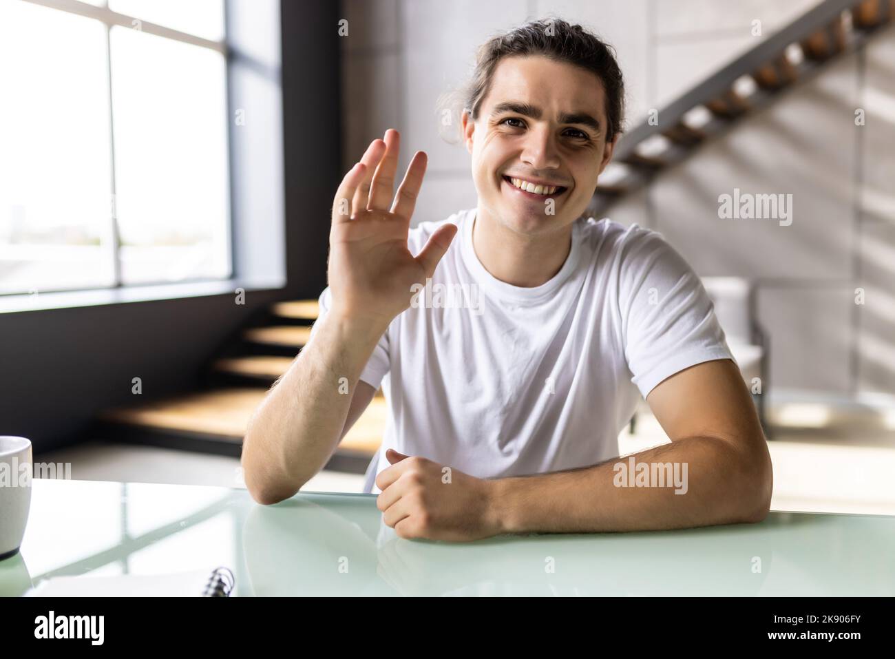 Portrait happy smiling young man waving hand, looking at camera ...