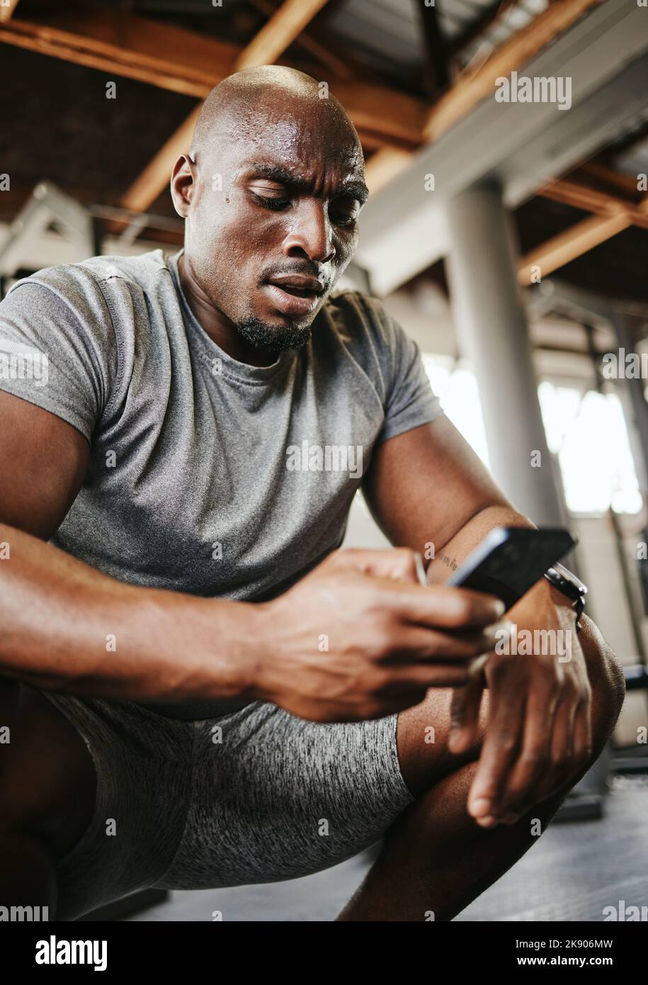 Phone, fitness and sweat with a black man athlete checking his social ...