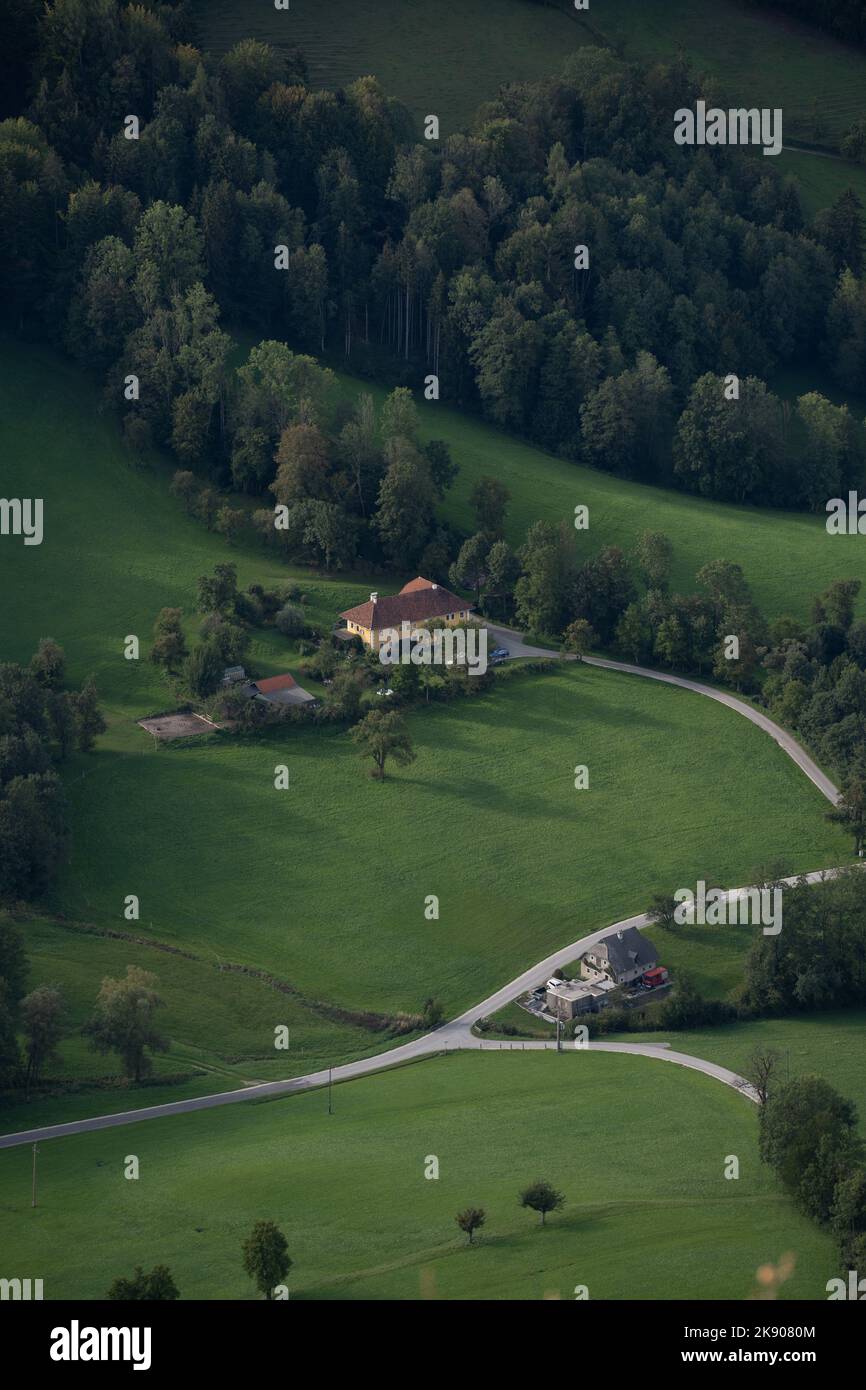 A single, countryside house surrounded by pasture and dense forest ...
