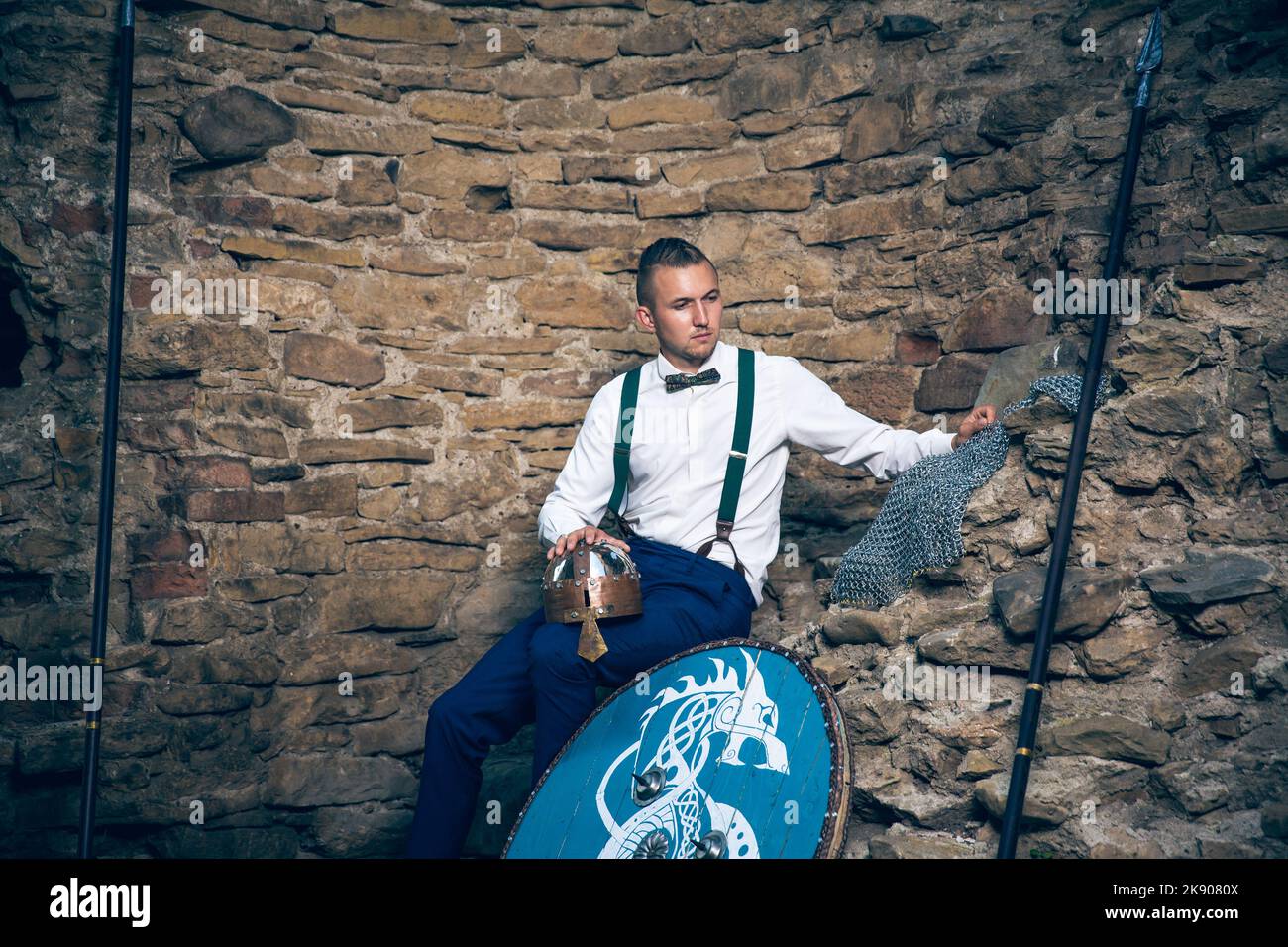 A man in a suit with a shield and a spear in his hands posing at an ...