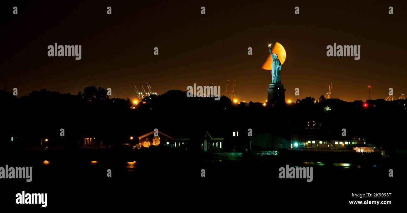 The Statue of Liberty before an orange scenic half-moon at night Stock ...