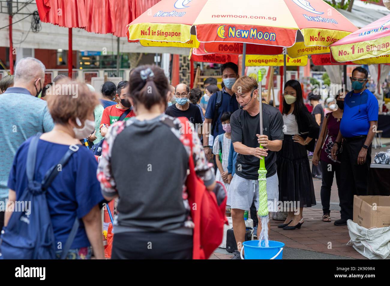 A seller demonstrating a cleaning mop to a crowd in Waterloo Street ...