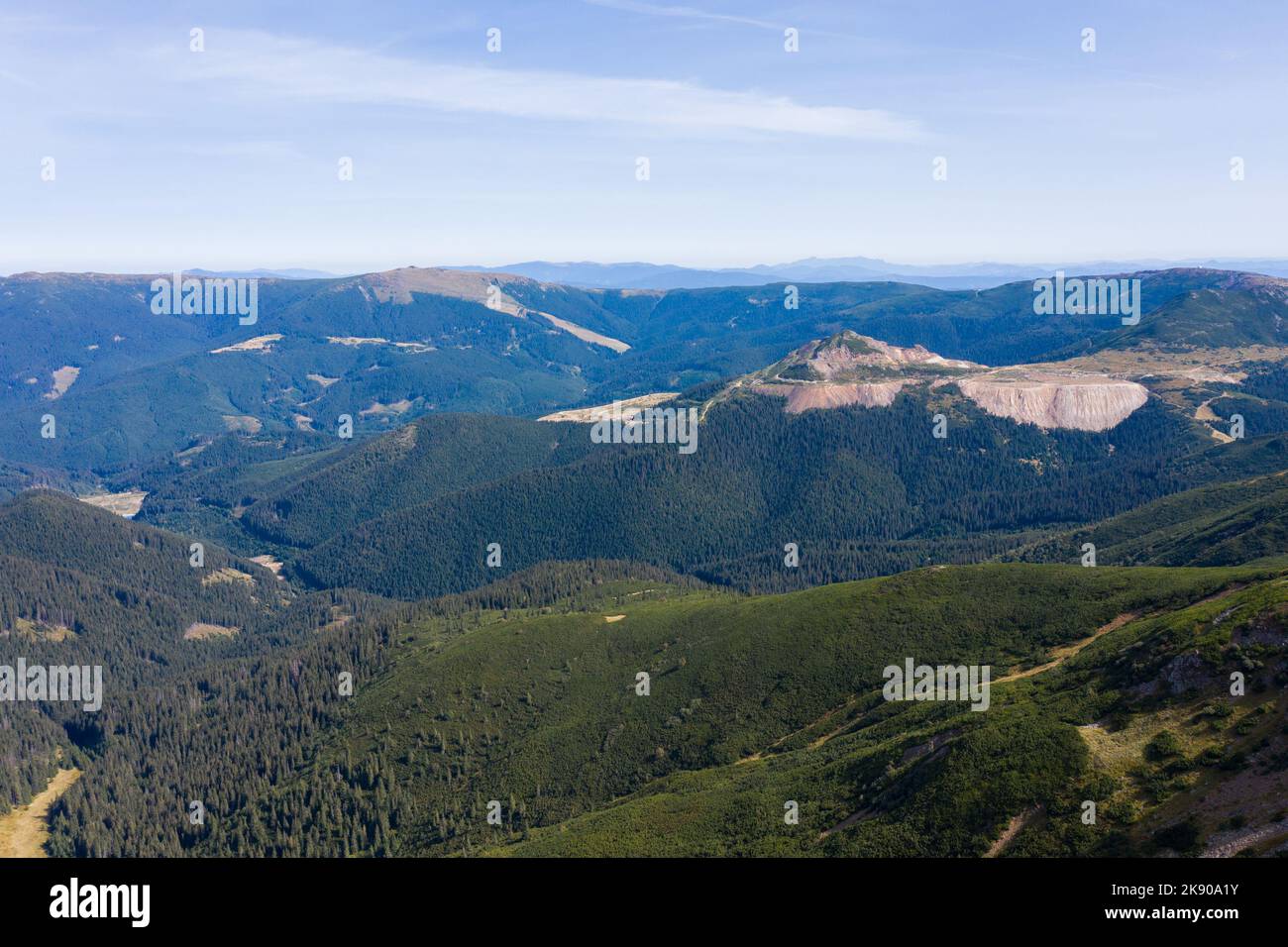 Stunning view of layered mountain ranges covered with dense pine forest and green valley under ...