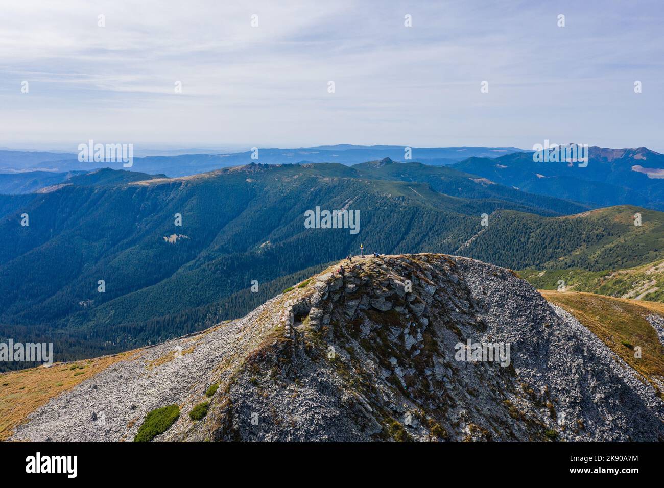 Stunning view of blue cloudy sky over layered mountain ranges and valley covered with vegetation ...
