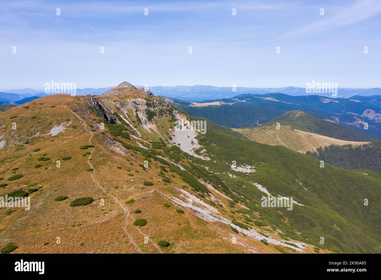 Stunning view of blue cloudy sky over layered mountain ranges and valley covered with vegetation ...