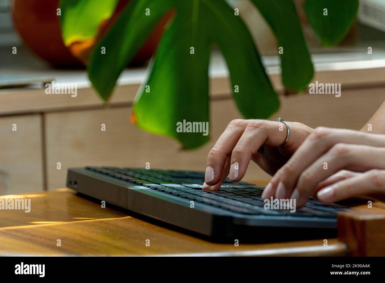 A closeup of a lady's hands typing on a wireless keyboard on her ...