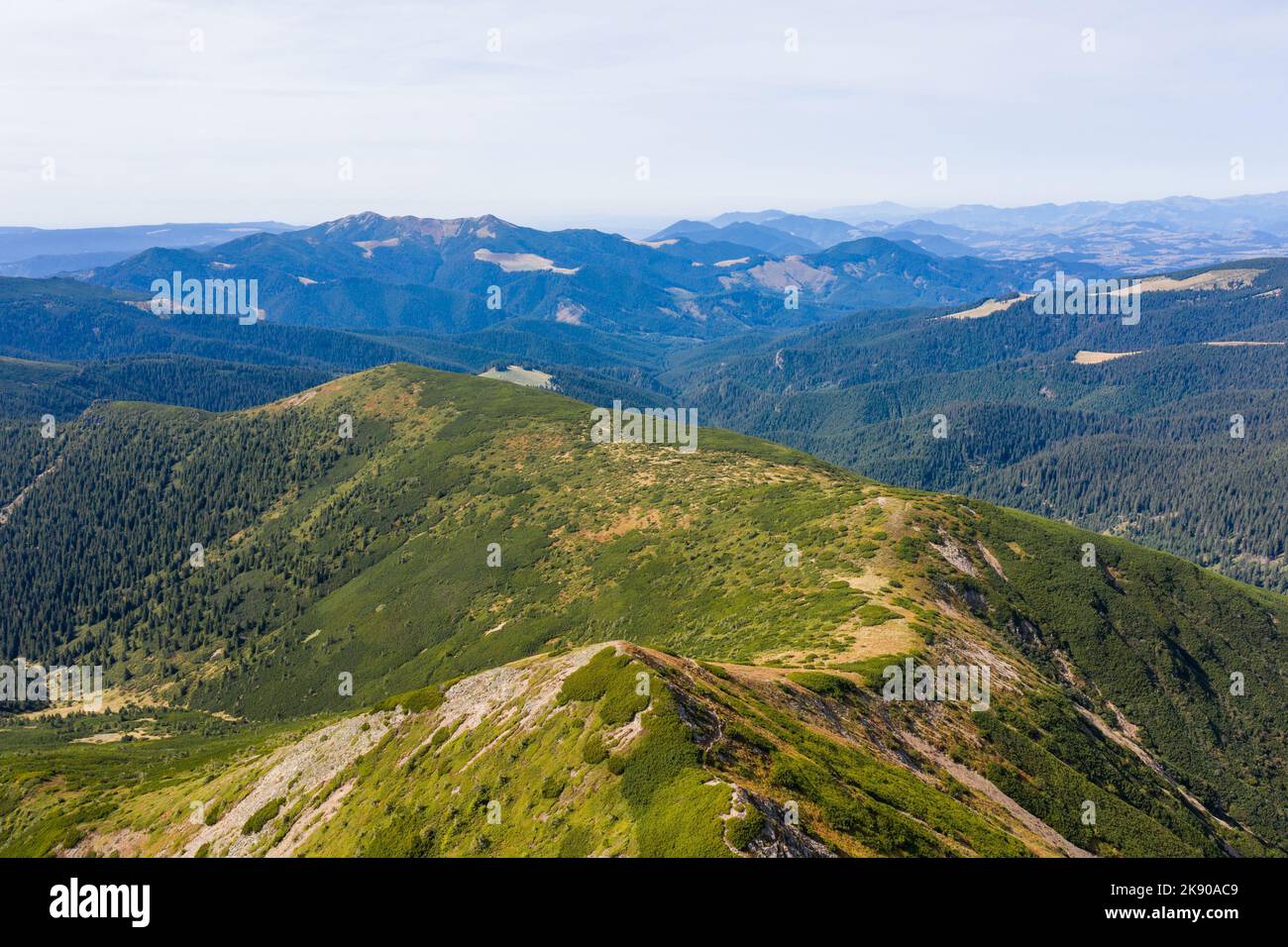 Stunning view of blue cloudy sky over layered mountain ranges and valley covered with vegetation ...
