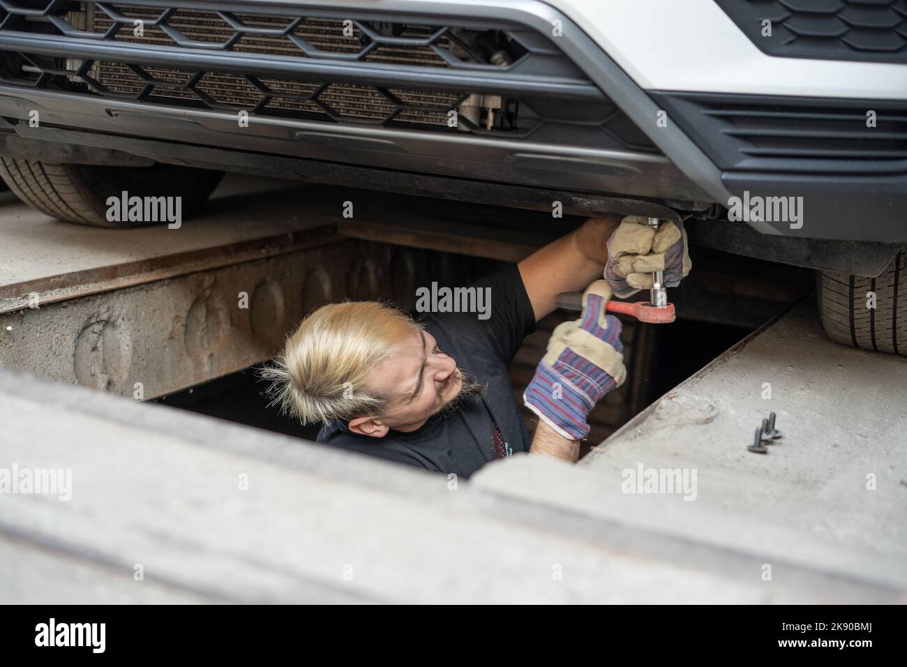 The mechanic services the car under the car Stock Photo - Alamy