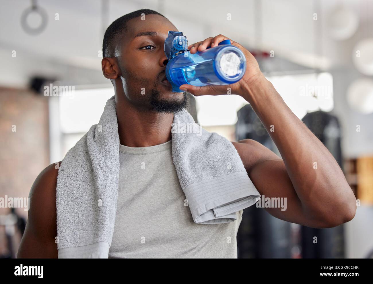 Water, drink and fitness with a sports man in a gym for exercise while ...