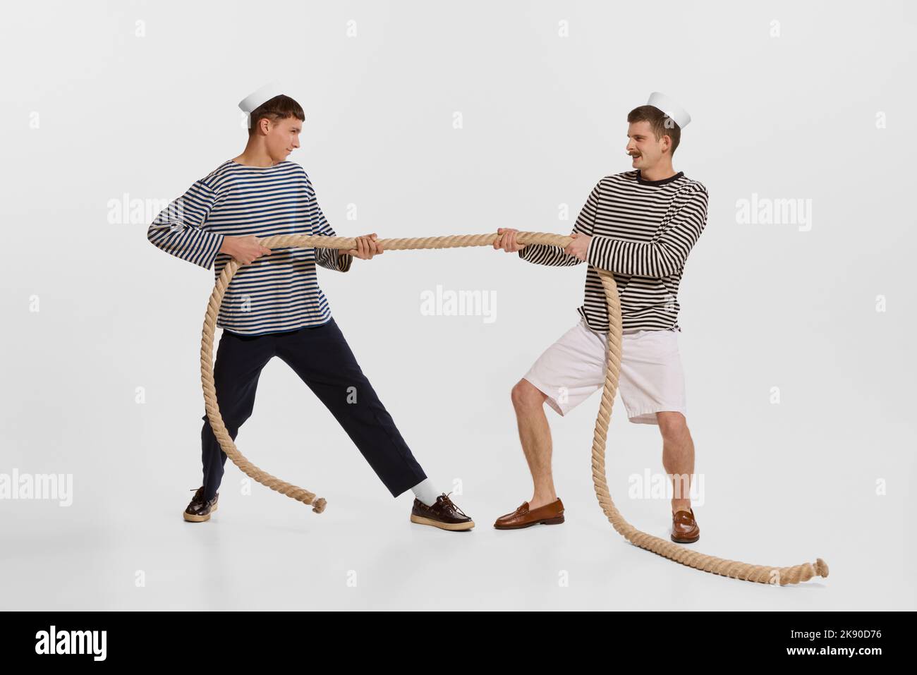 Portrait of two young boys, sailor, seamen in striped shirts pulling ...