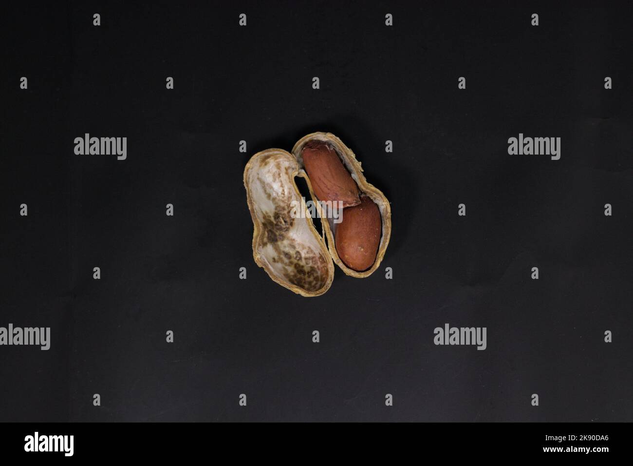 Cracked Shelled peanut with two nuts inside on a black surface Stock ...