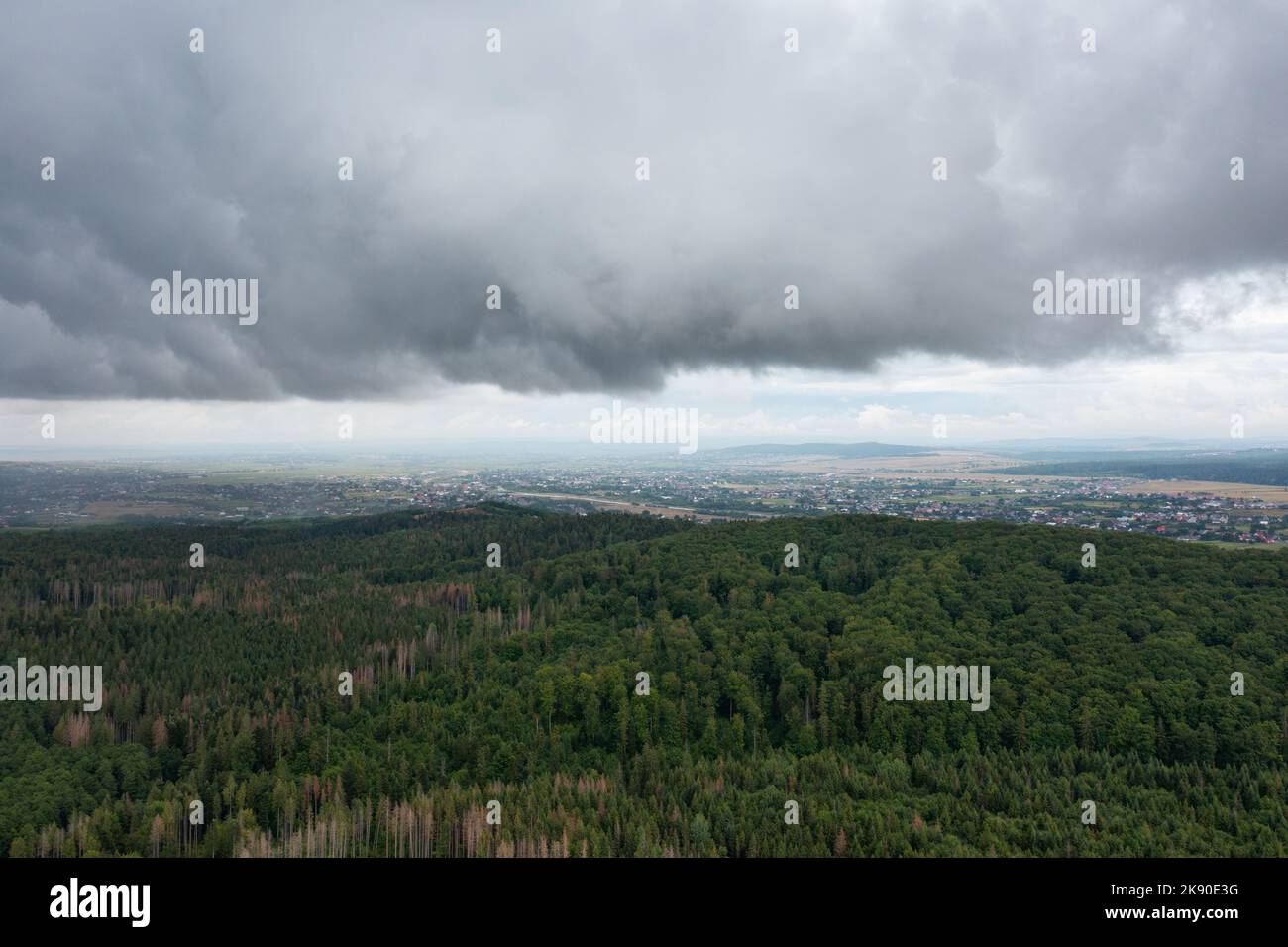 Stunning view of layered mountain ranges covered with dense pine forest and small town in valley ...