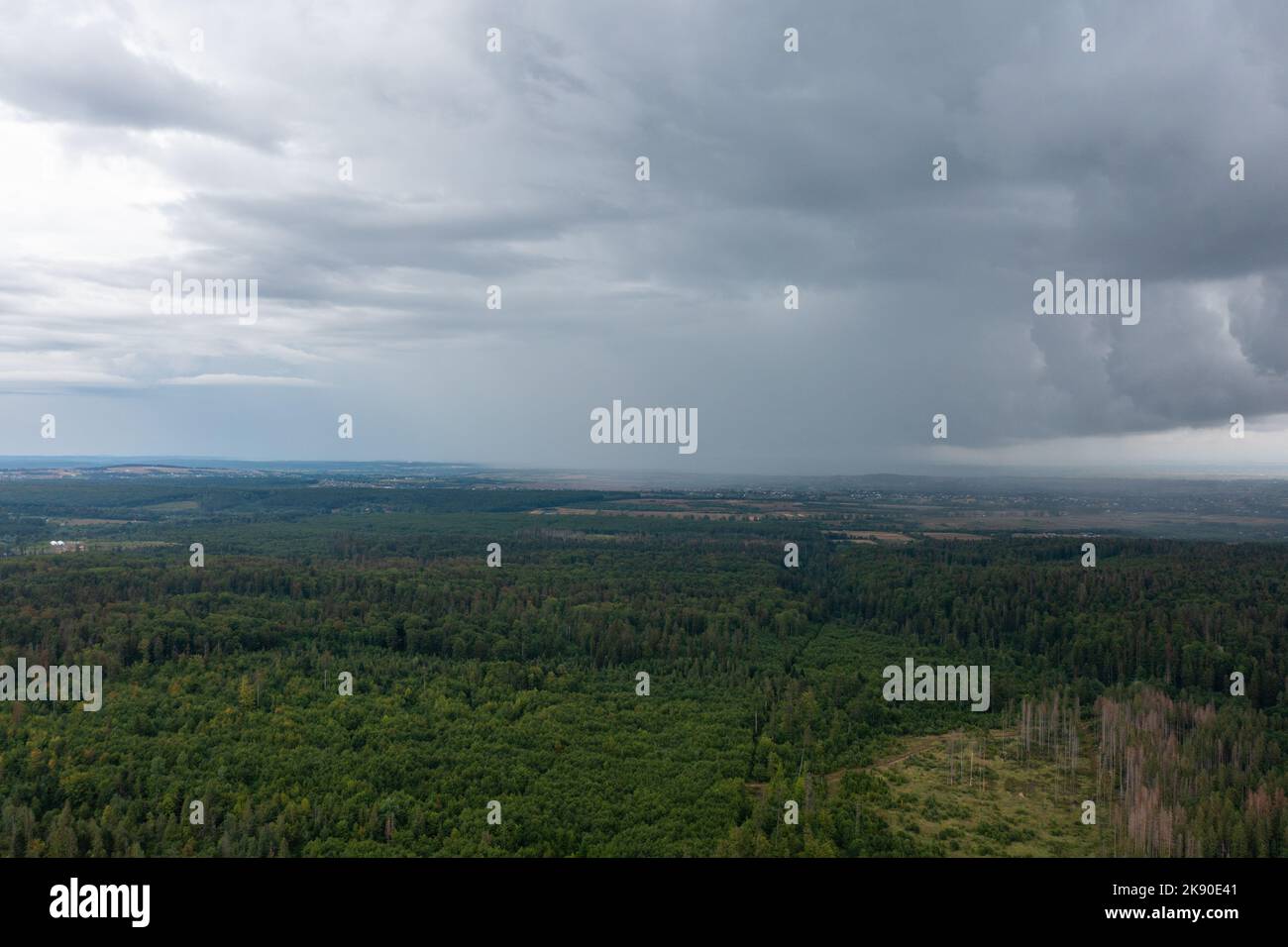 Stunning view of layered mountain ranges covered with dense pine forest and small town in valley ...