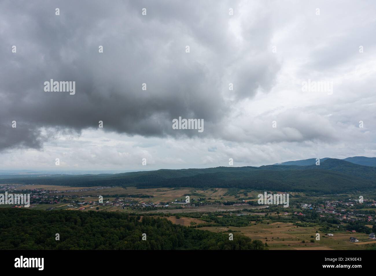 Stunning view of layered mountain ranges covered with dense pine forest and small town in valley ...