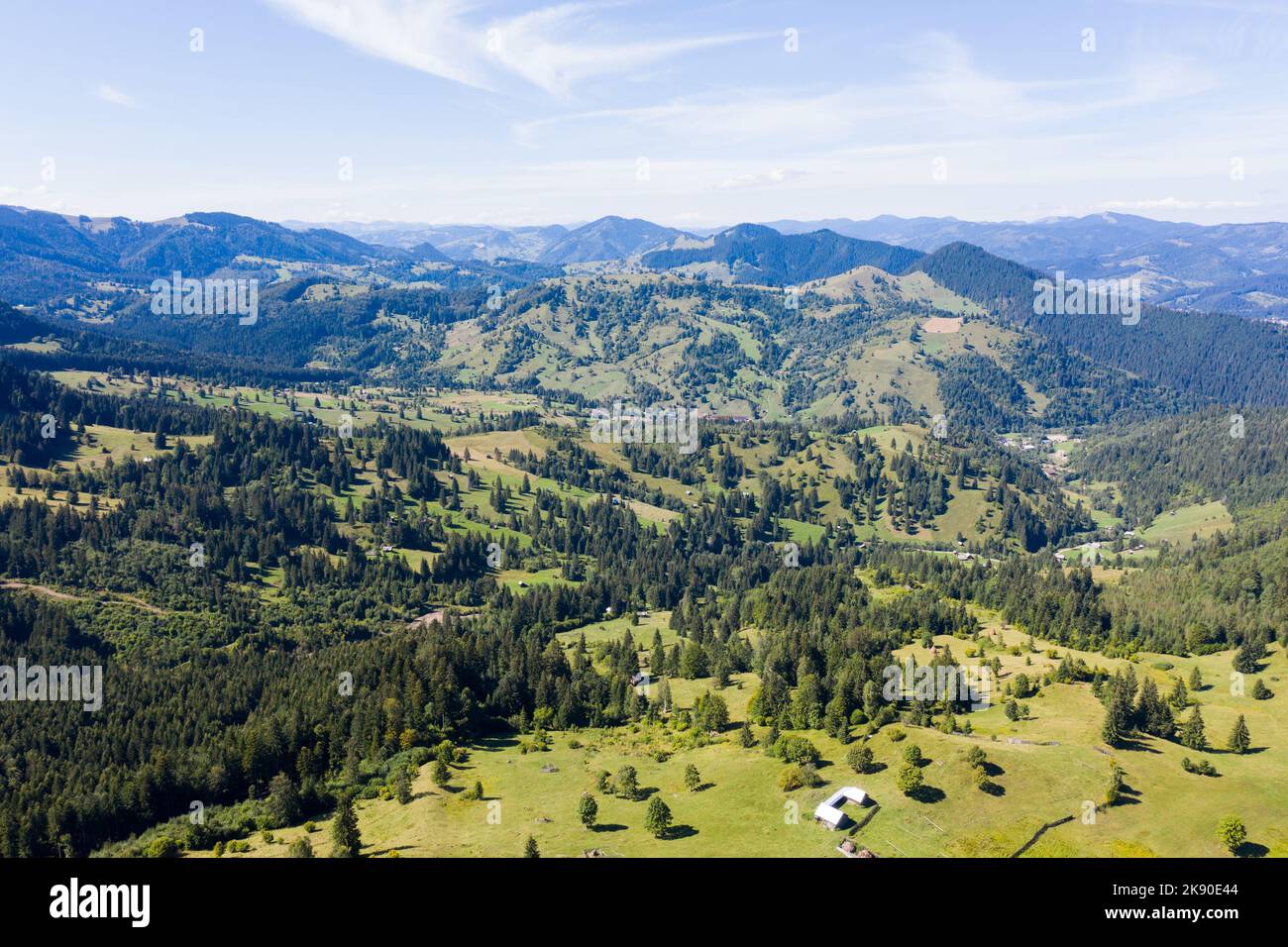 Stunning view of layered mountain ranges covered with dense pine forest and green valley under ...