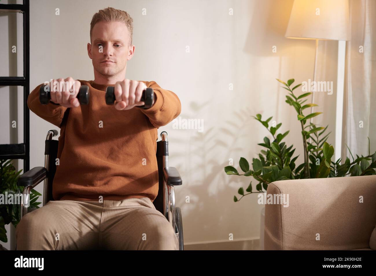 Young man with disability doing exercise with small dumbbells to train ...