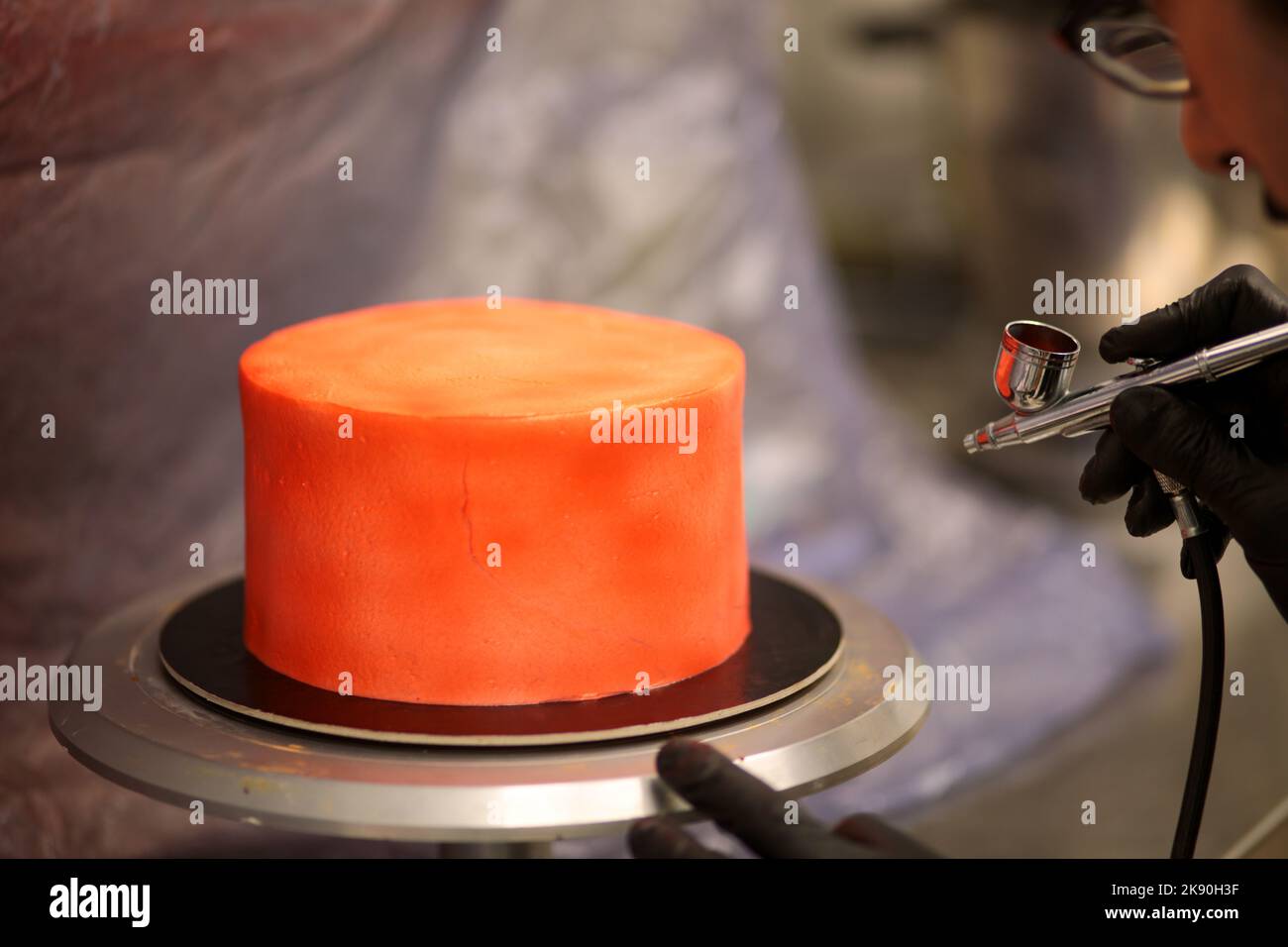 cook preparing a red frosted cake using air bush Stock Photo - Alamy