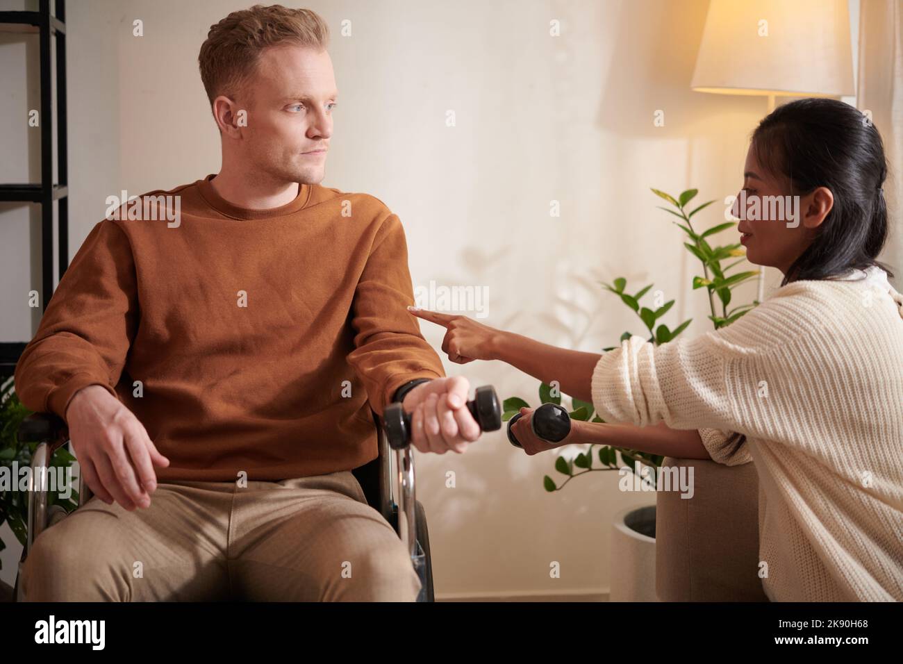 Physical therapeutist visiting man with disability at home and ...