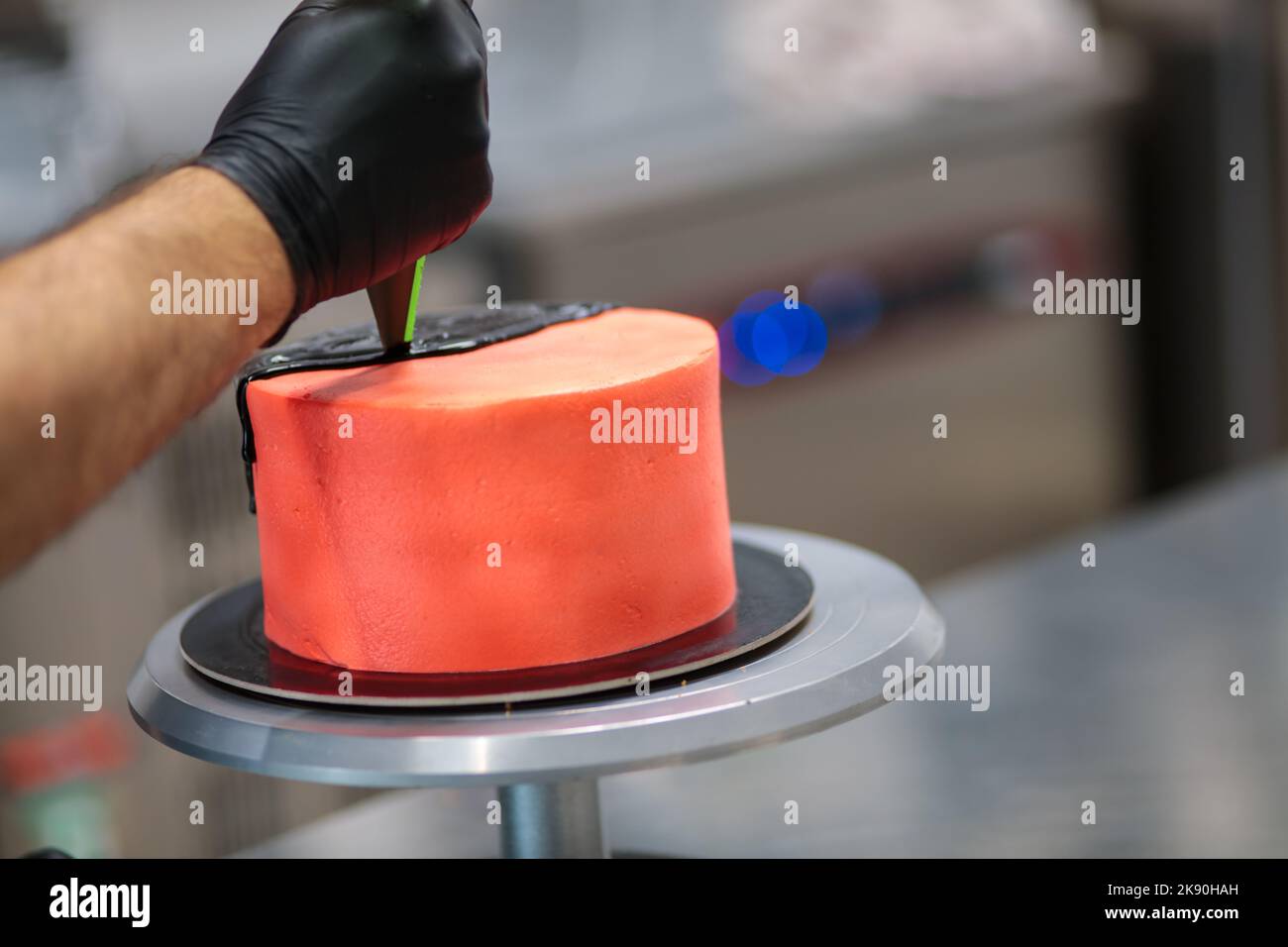 topping a red cake with black dark chocolate icing Stock Photo - Alamy