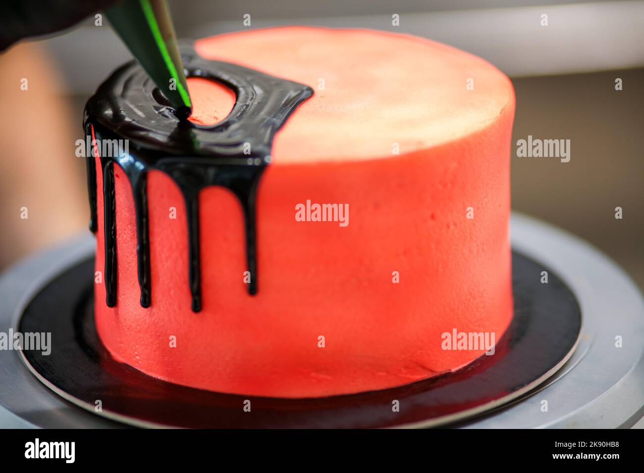 topping a red cake with black dark chocolate icing Stock Photo - Alamy