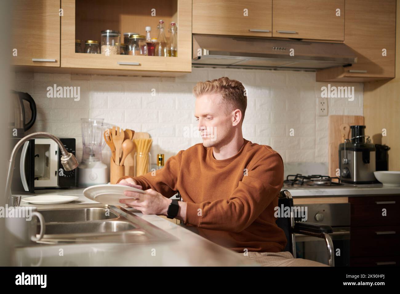Young man with disability washing dishes in kitchen sink Stock Photo ...