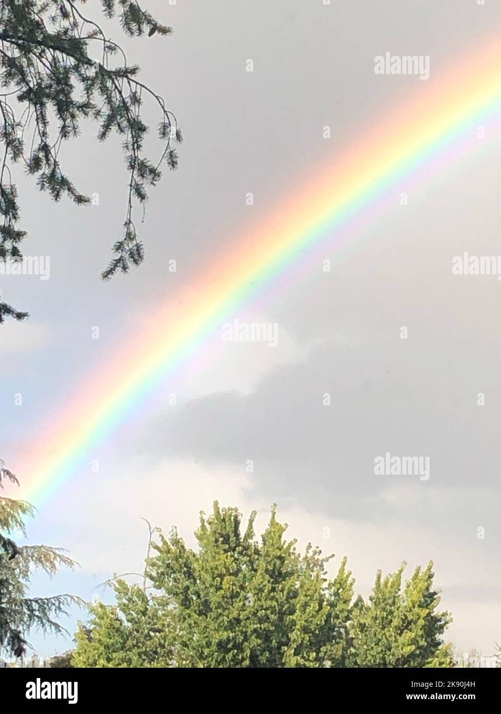A rainbow in the cloudy sky, vertical Stock Photo - Alamy