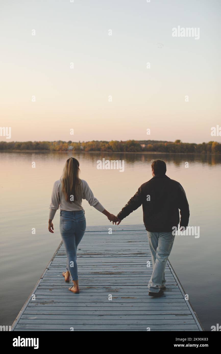 Romantic couple walking hand in hand by the pier Stock Photo - Alamy