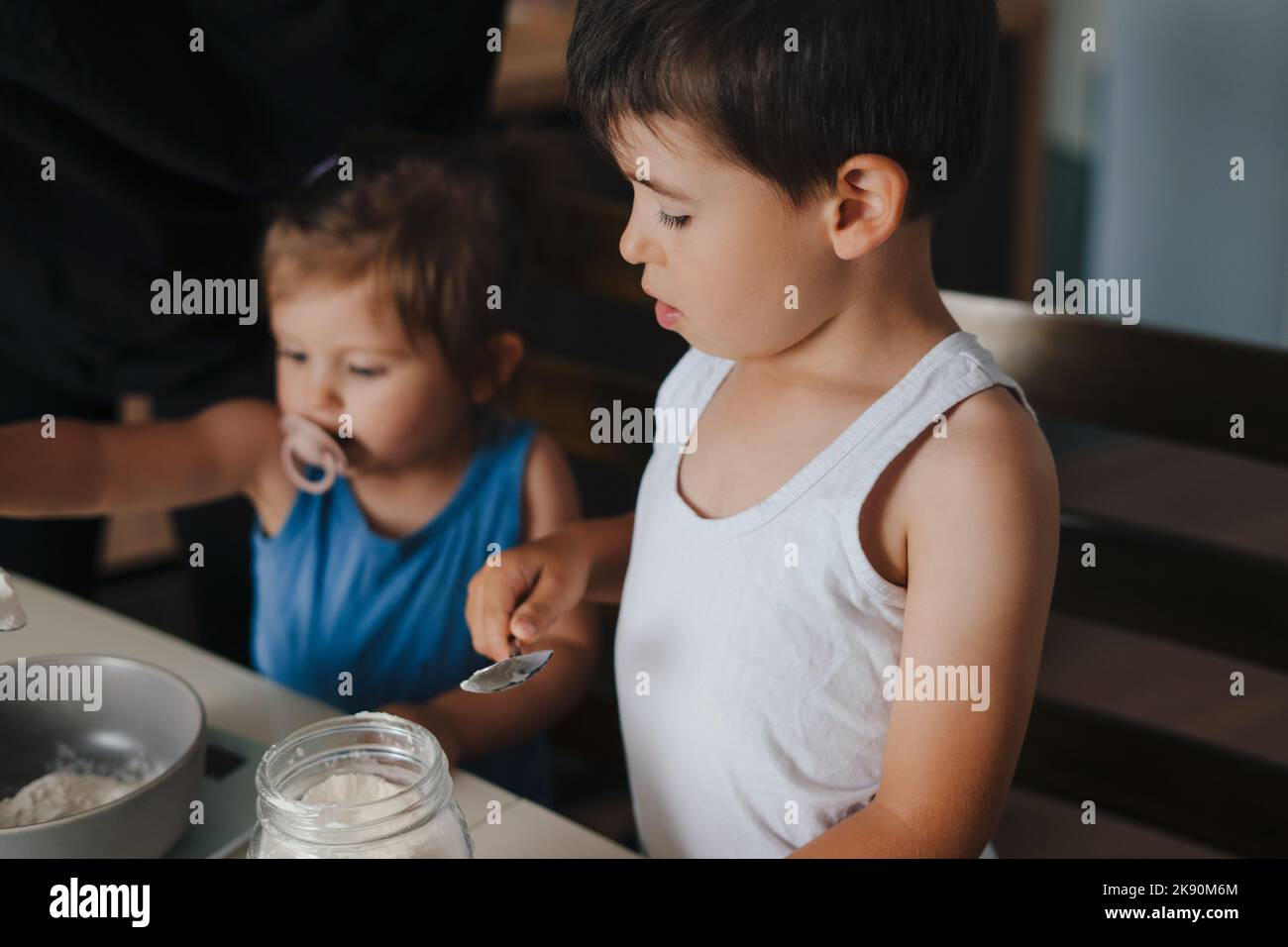 Close-up view of two kids adjusting kitchen scale for weighing ...
