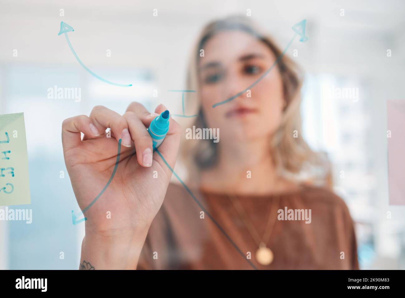 Strategy, idea and woman writing on glass board with blue marker ...