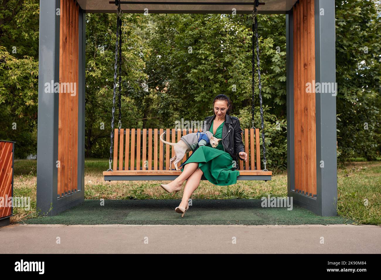 The young woman is holding her cat in amoveralls on her feet. Cat on a ...
