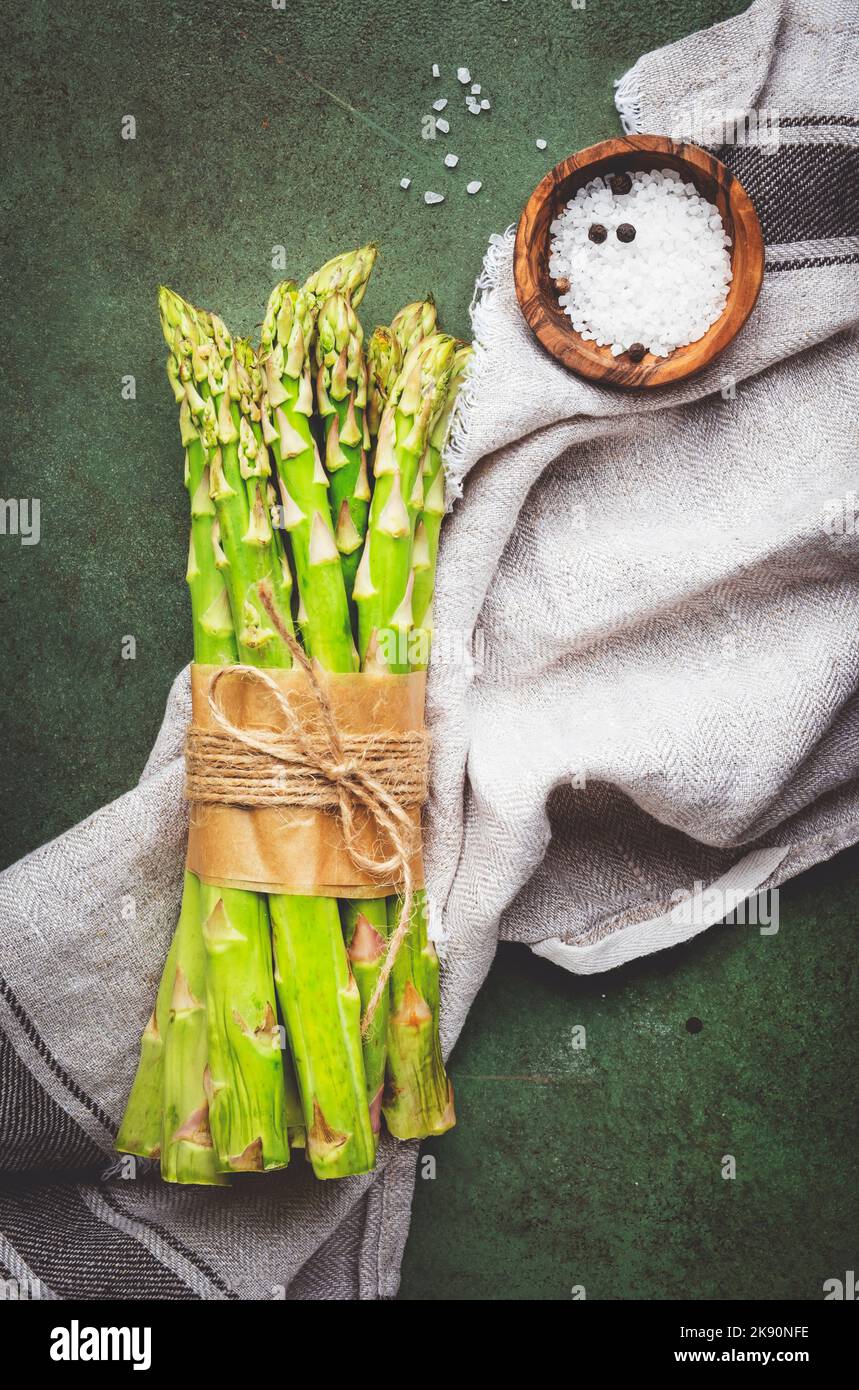Fresh asparagus bunch and sea salt on gray napkin on green table ...