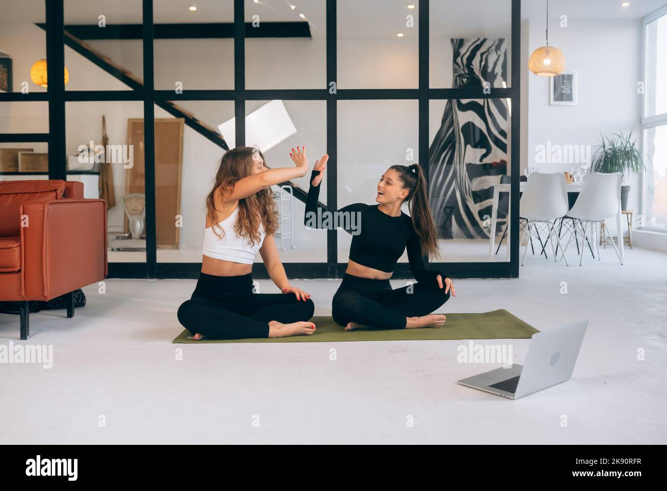 Two women while sitting in the lotus position give a high five Stock ...