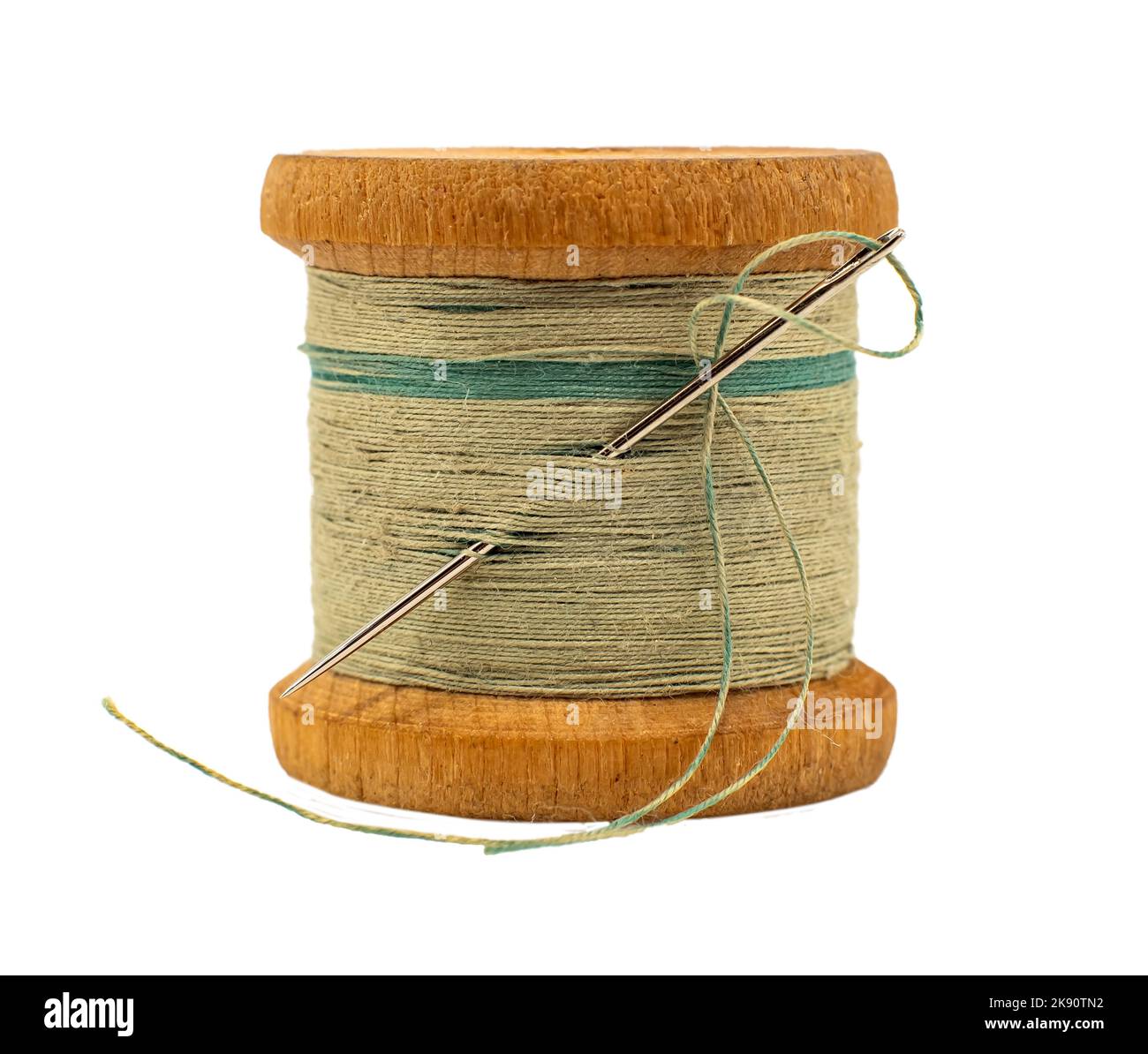An old wooden spool of thread and a needle on a white background close ...