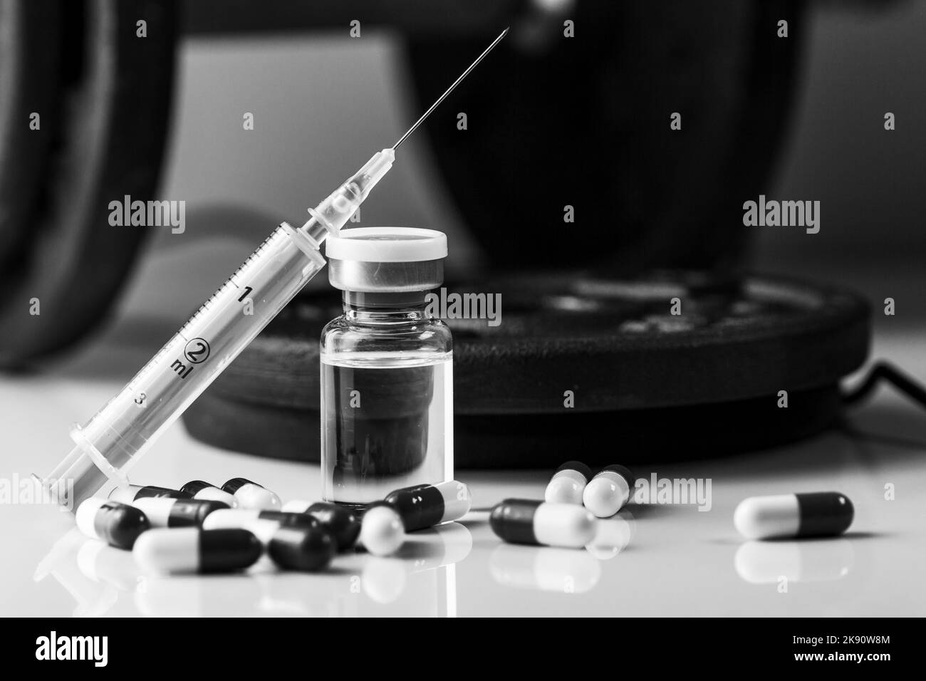 A black and white pharmaceutical syringe with needle and medical pills ...